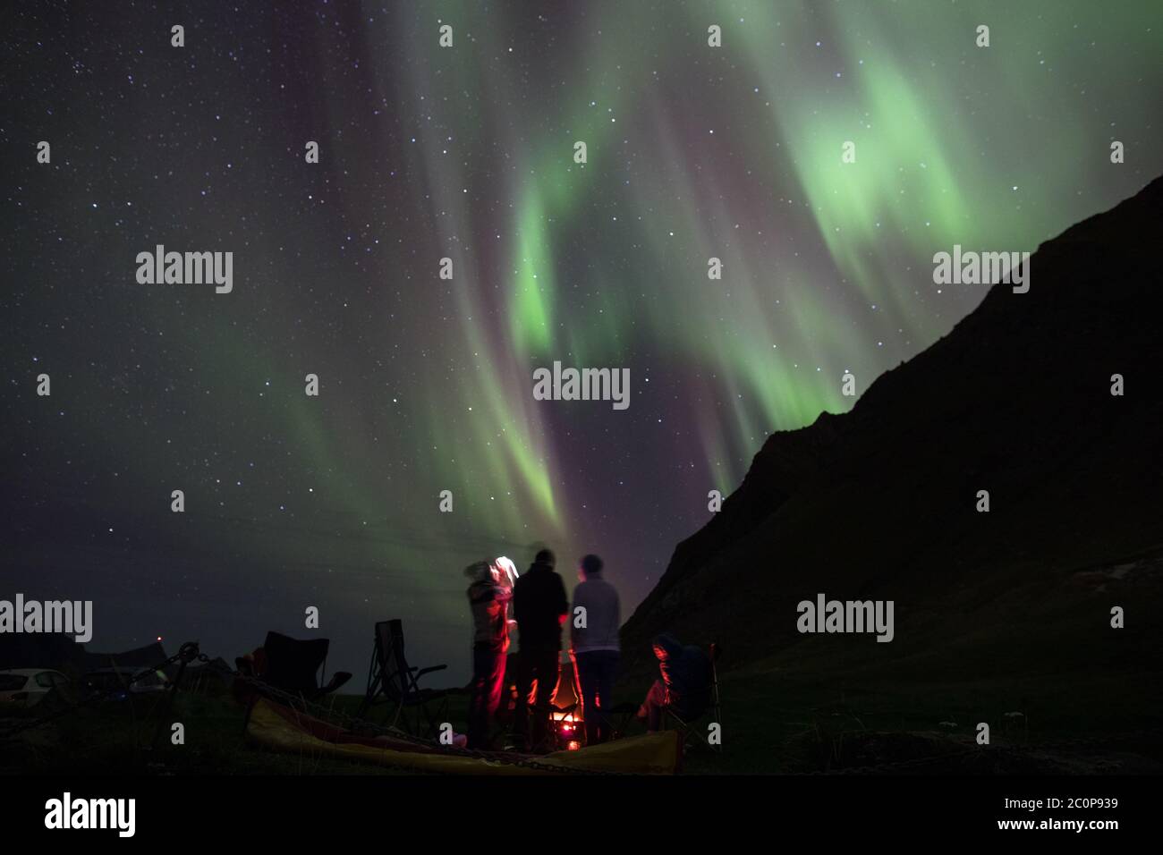 Friends round a camp fire under the northern lights Stock Photo - Alamy