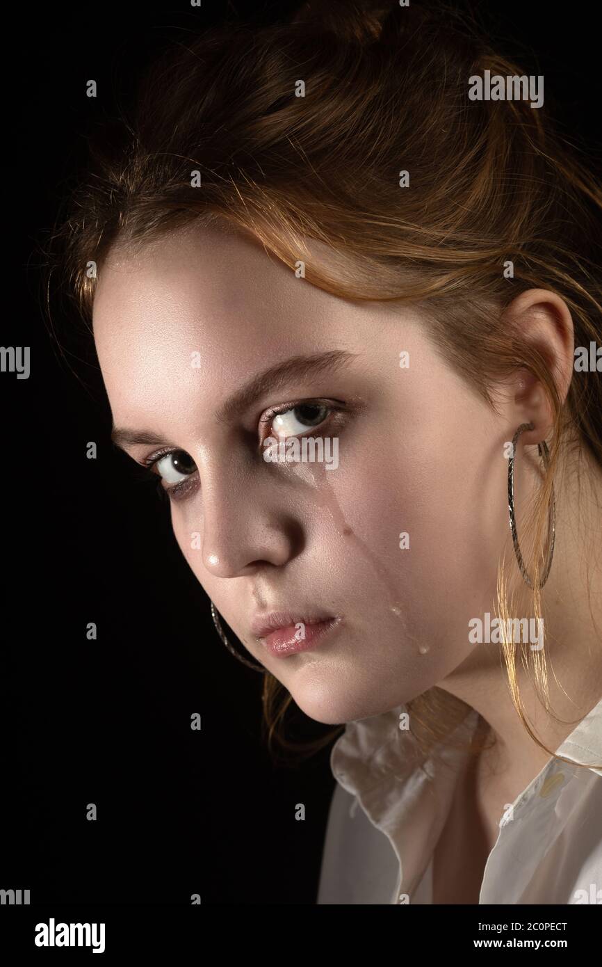 sad woman crying, looking at camera on black background, closeup ...