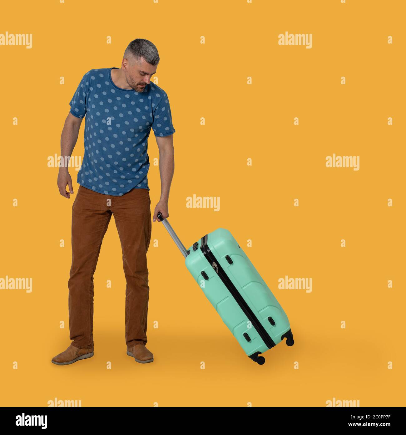 Middle-aged man carrying plastic suitcase on wheels holding it by ...