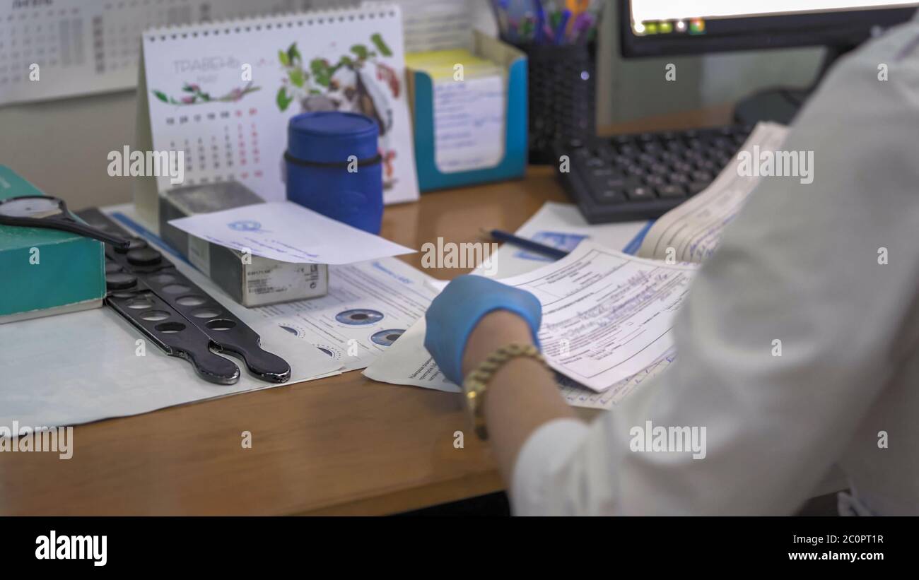 Doctor works in ophthalmologist office. Medic writes medical forms ...