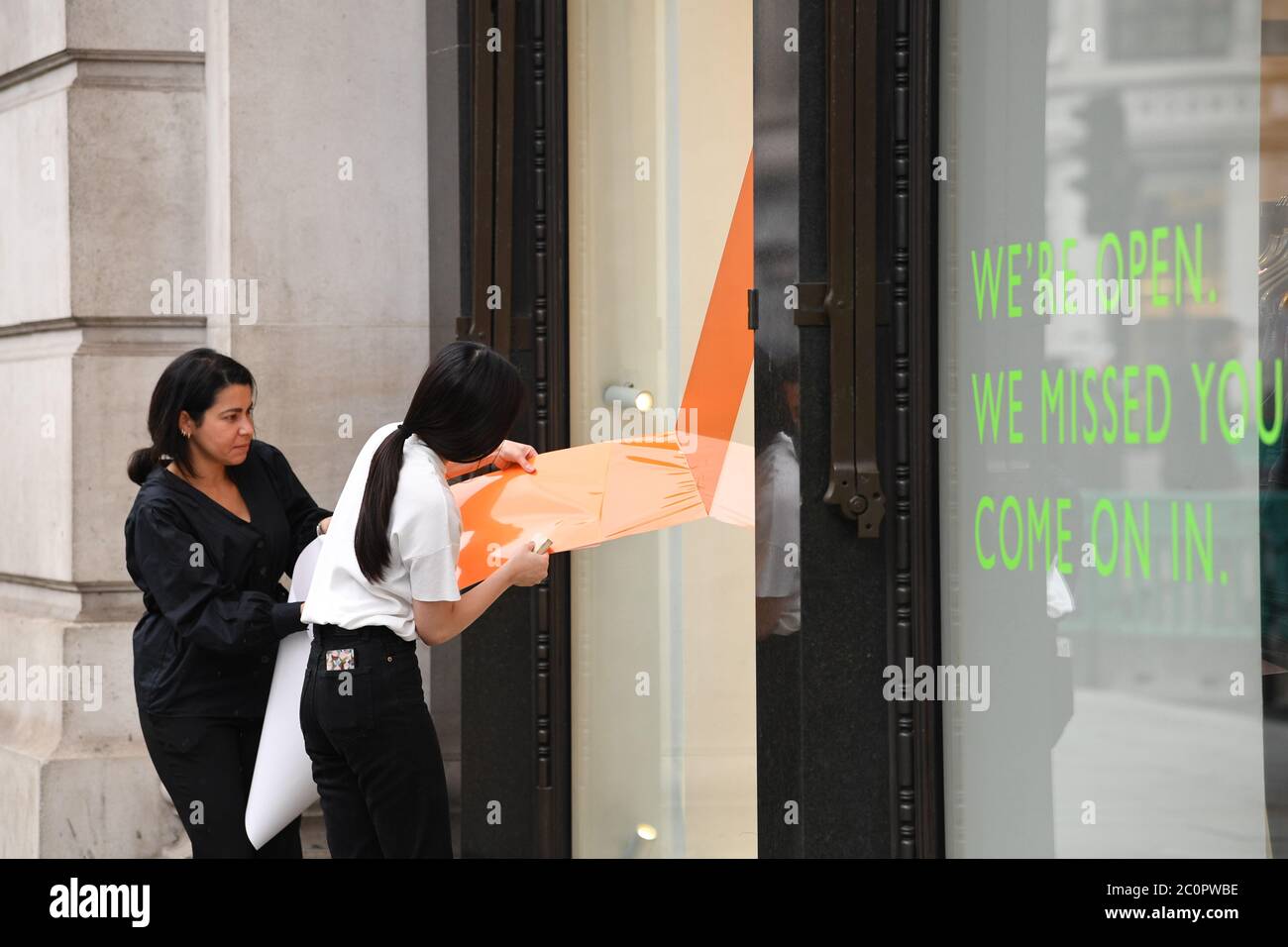 Shop staff putting up a sign on a shop window in Regent Street in ...