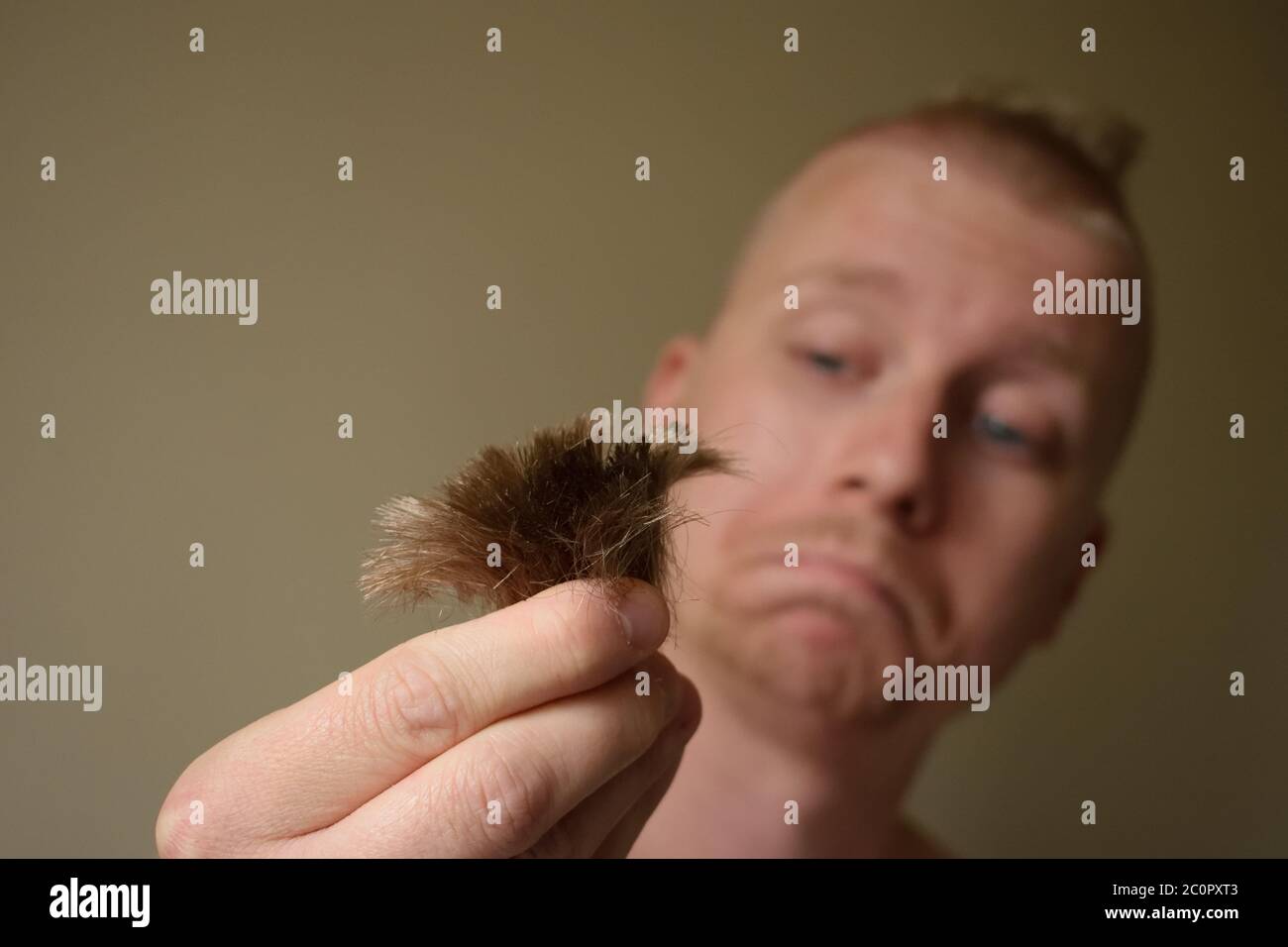 Young Man Looks Regretfully at a Lock of His Hair After Giving Himself ...