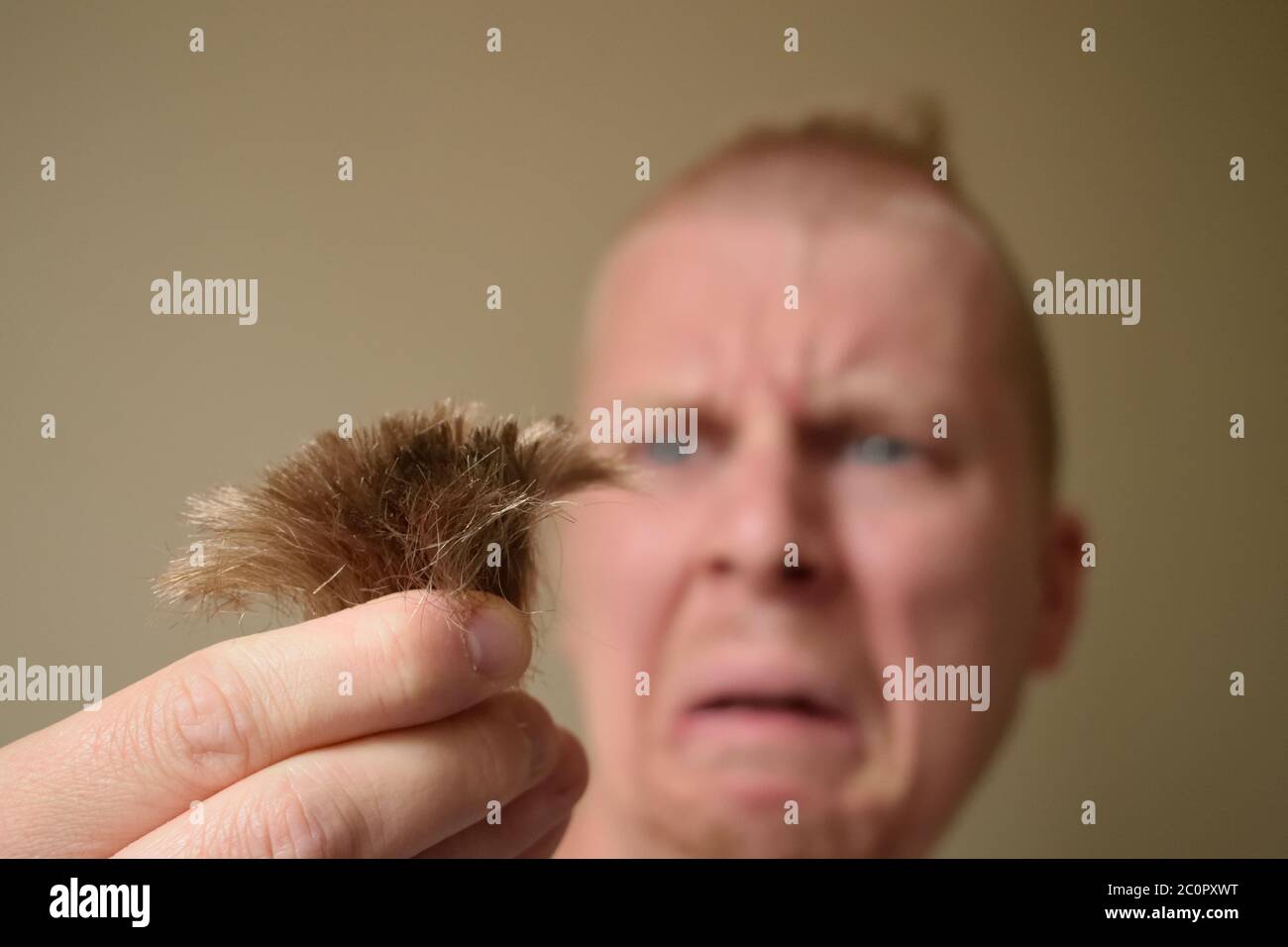 Young Man Looks Regretfully at a Lock of His Hair After Giving Himself ...