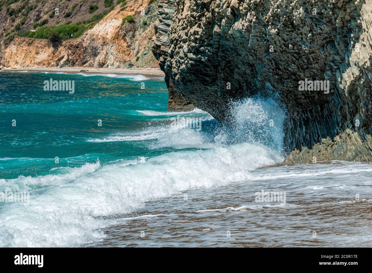 ocean wave crashing into the coastal columnar basalt rocks, as in ...