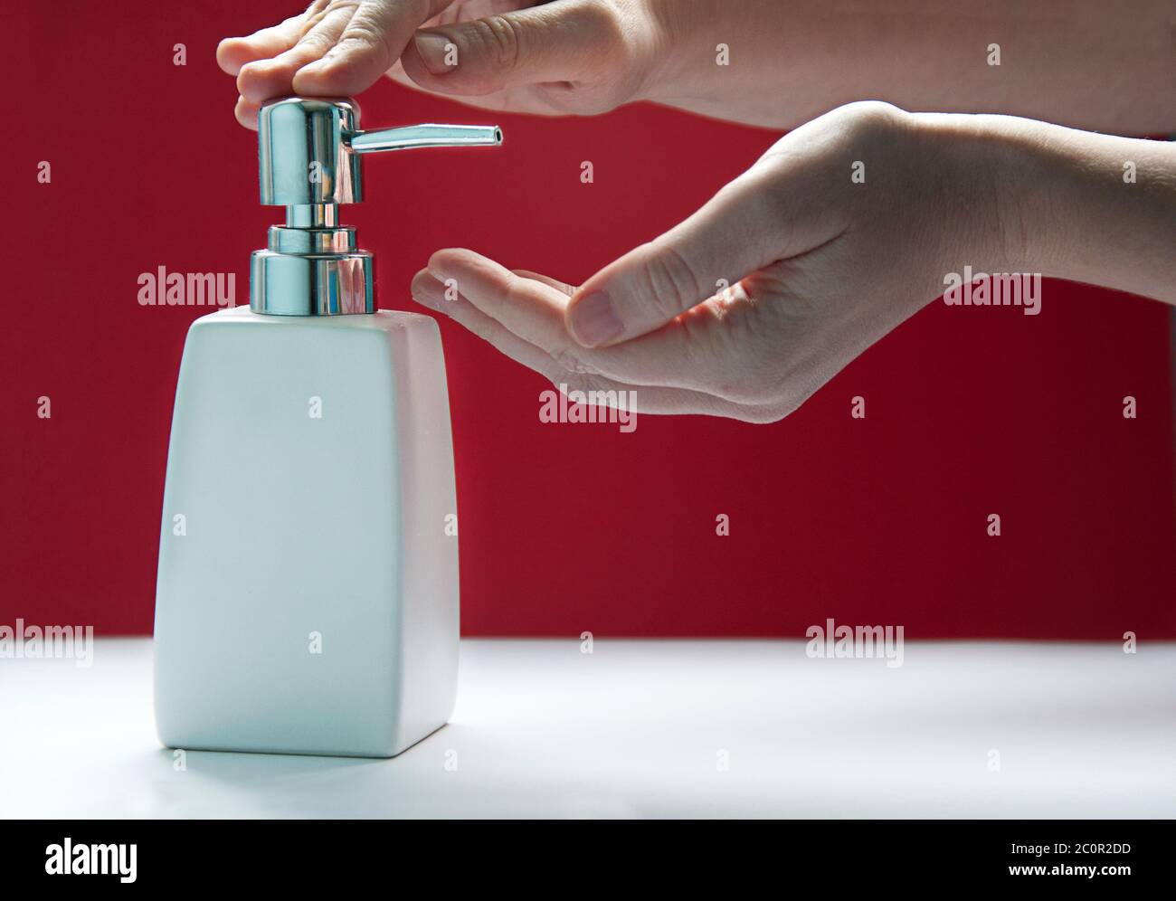 Woman hands using a soap dispenser on a pink and white background Stock ...