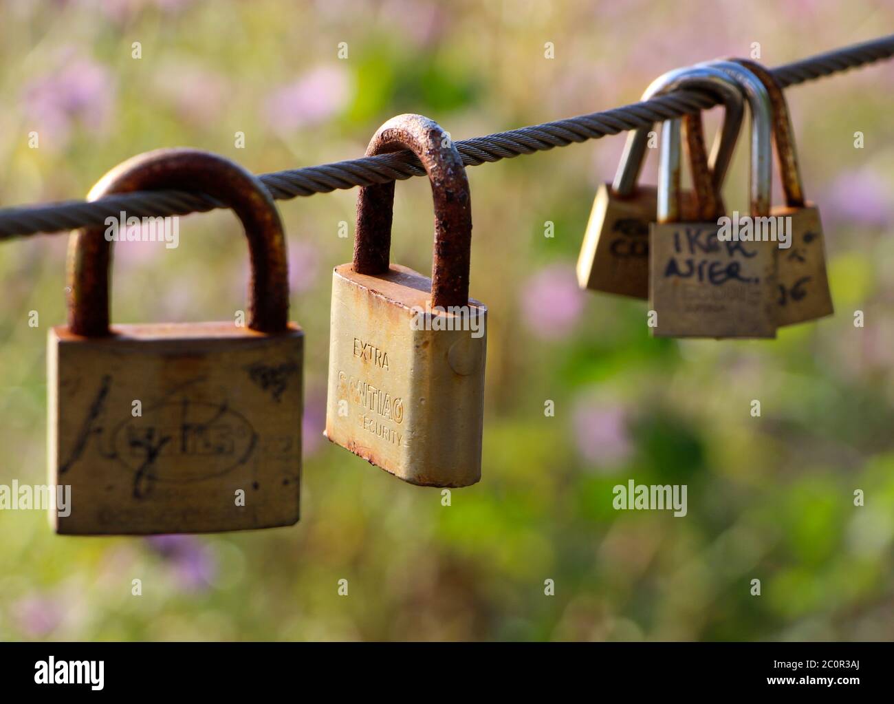 Padlocks hanging on a wire with Spanish names written Stock Photo - Alamy