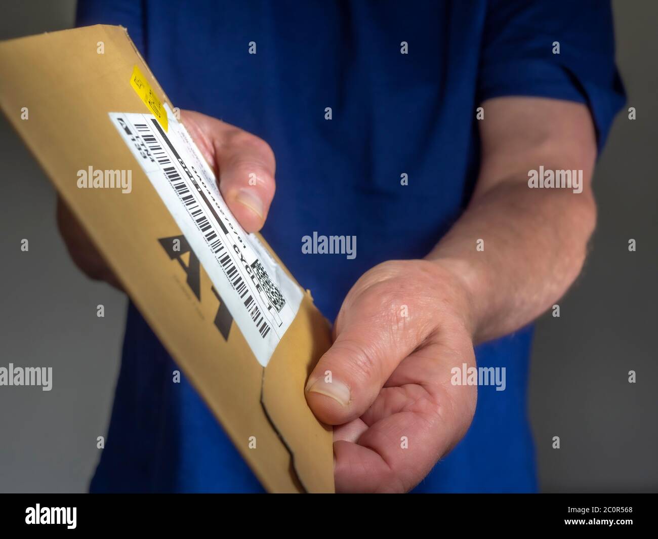 Man in a blue tee shirt delivering a small package, by handing over a ...