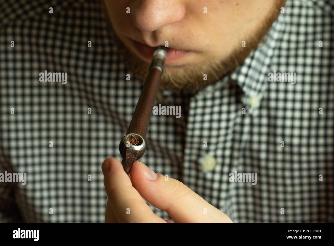 Bearded man with a pipe smoking tobacco in his mouth Stock Photo - Alamy