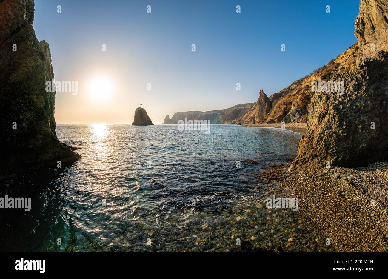 View of the sunset sea and the beach, the rock volcanic rock is lit by ...