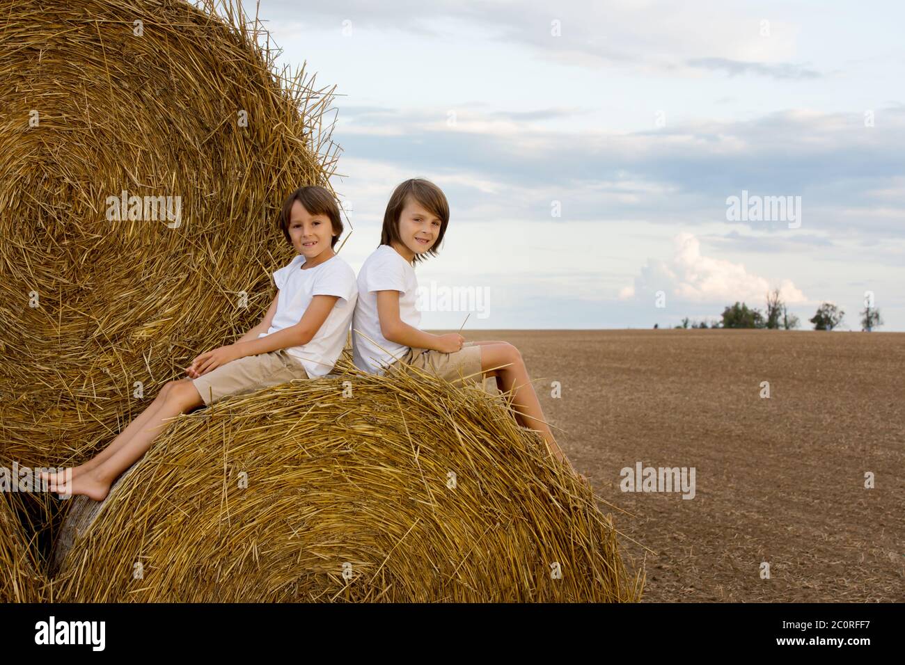 Happy children, playing on haystacks in a field, summertime Stock Photo ...