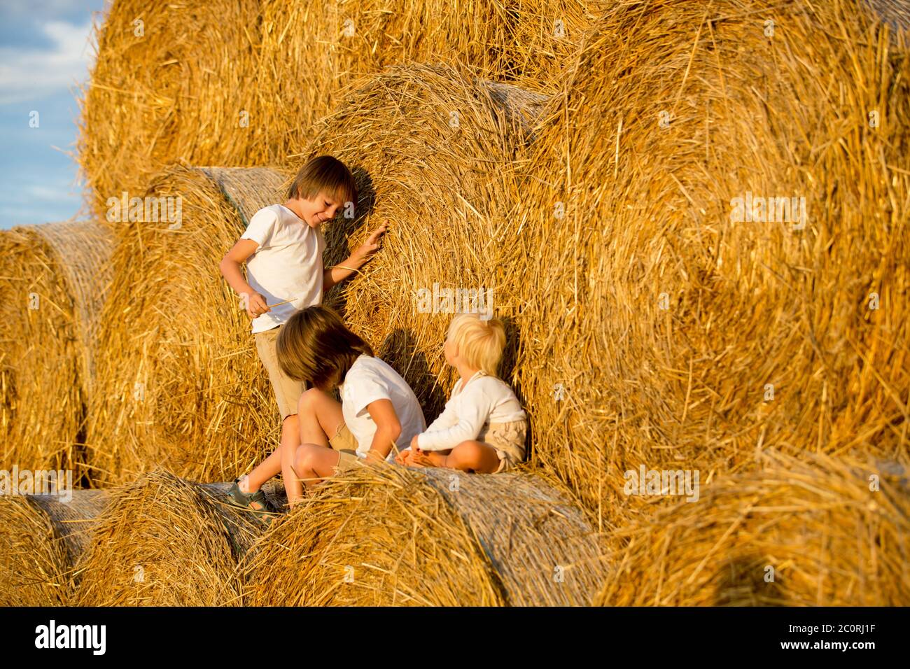 Happy children, playing on haystacks in a field, summertime Stock Photo ...