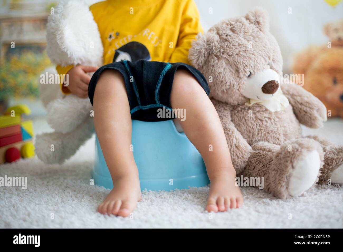 Cute toddler boy, potty training, playing with his teddy bear on potty ...