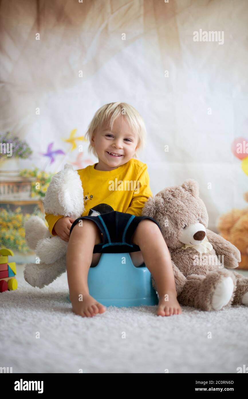 Cute toddler boy, potty training, playing with his teddy bear on potty ...