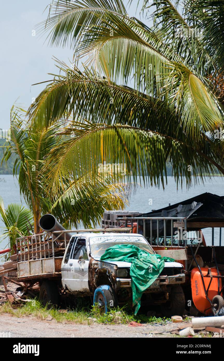 Junk broken Truck, trash and palm trees in front of the ocean with ...