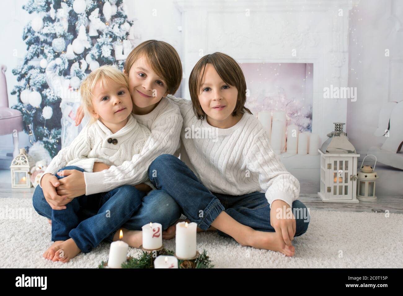 Three children, boy brothers, reading book at home at night on ...