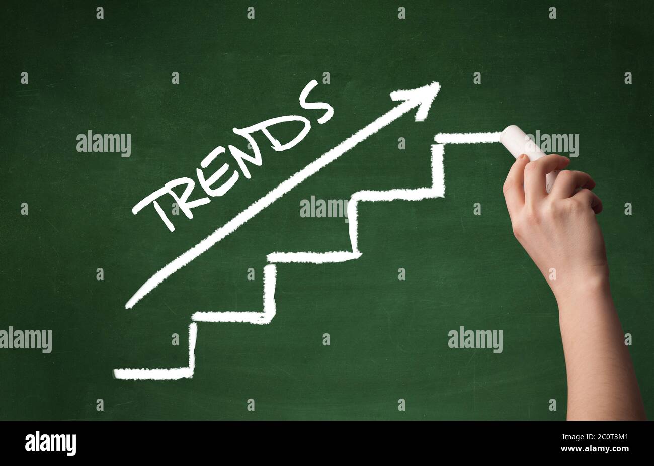 Hand drawing TRENDS inscription with white chalk on blackboard ...