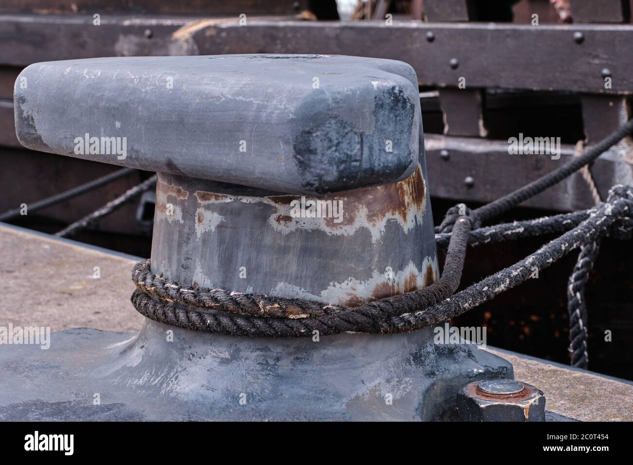 Large black mooring bollard with ropes or hawsers on the quay of the ...