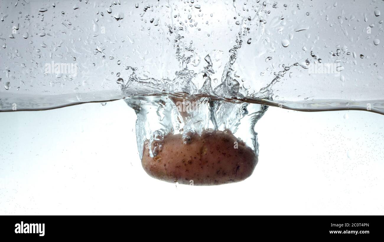 One potato thrown into the water, beautiful splashes of water, on a ...