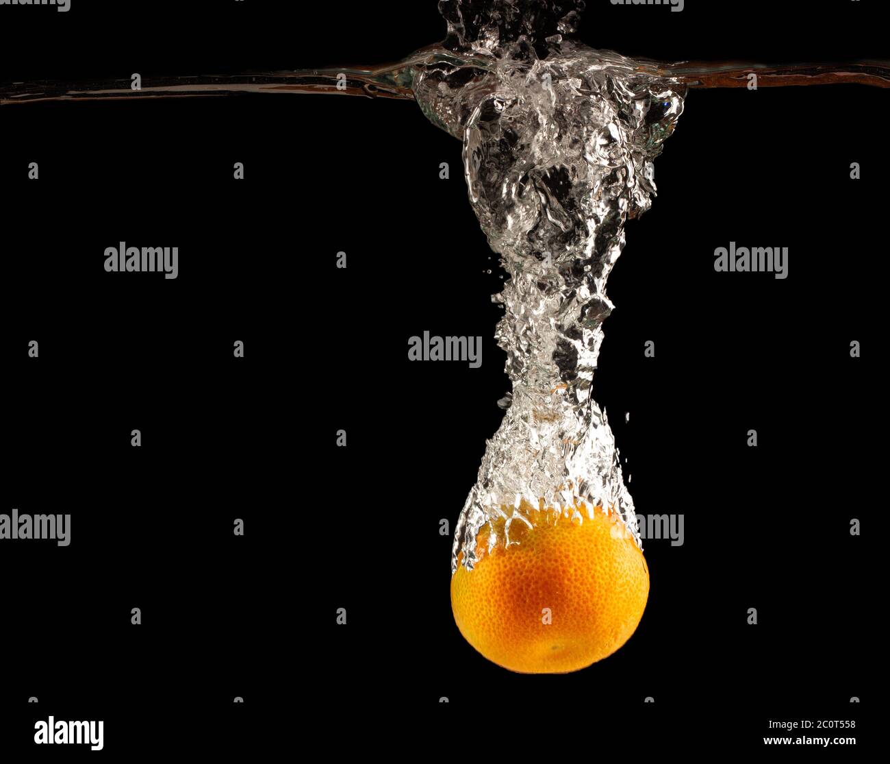 Mandarin falls into water creating spray on a black background Stock ...