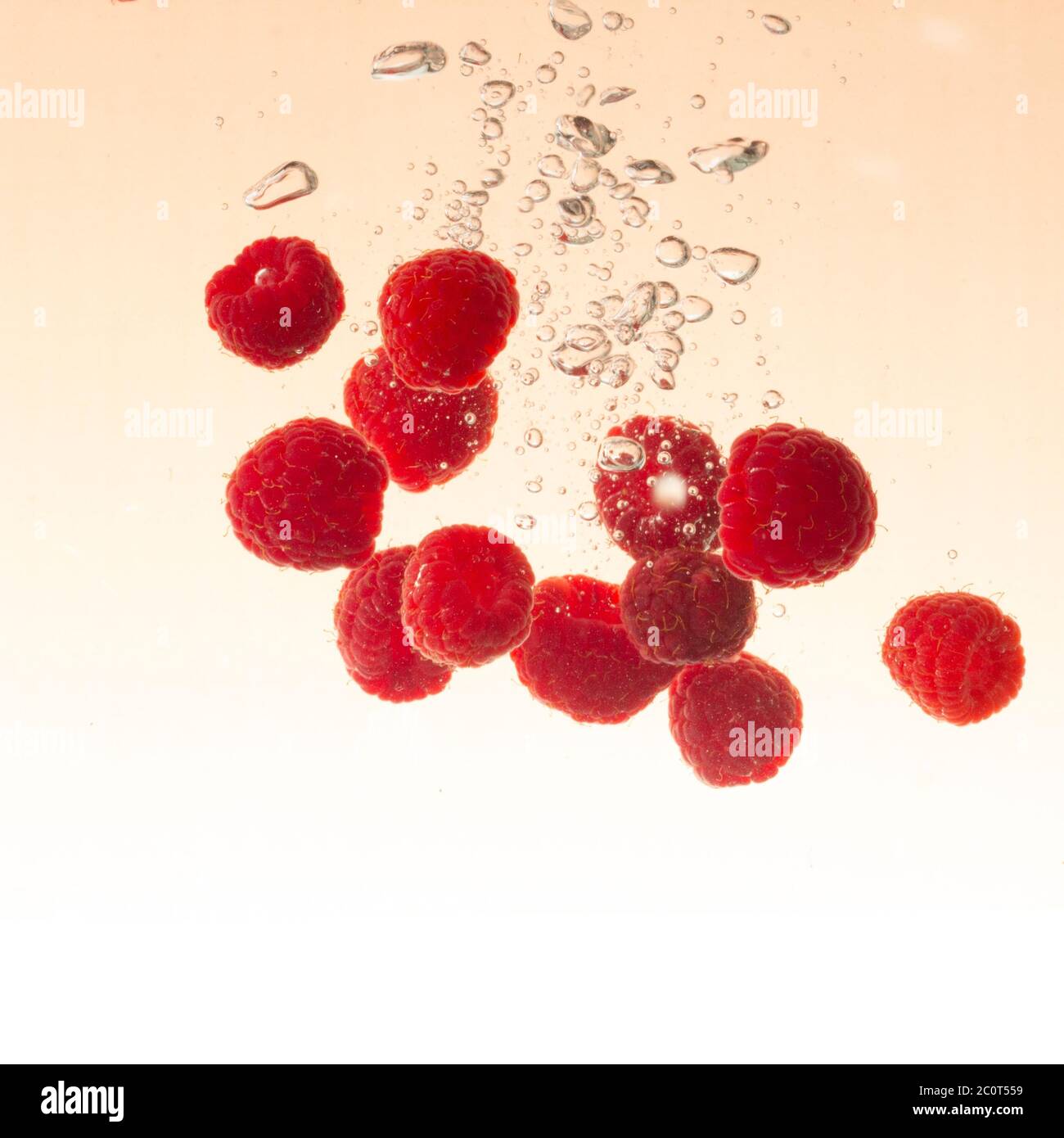 raspberry fruits making splash in water orange pastel background Stock ...