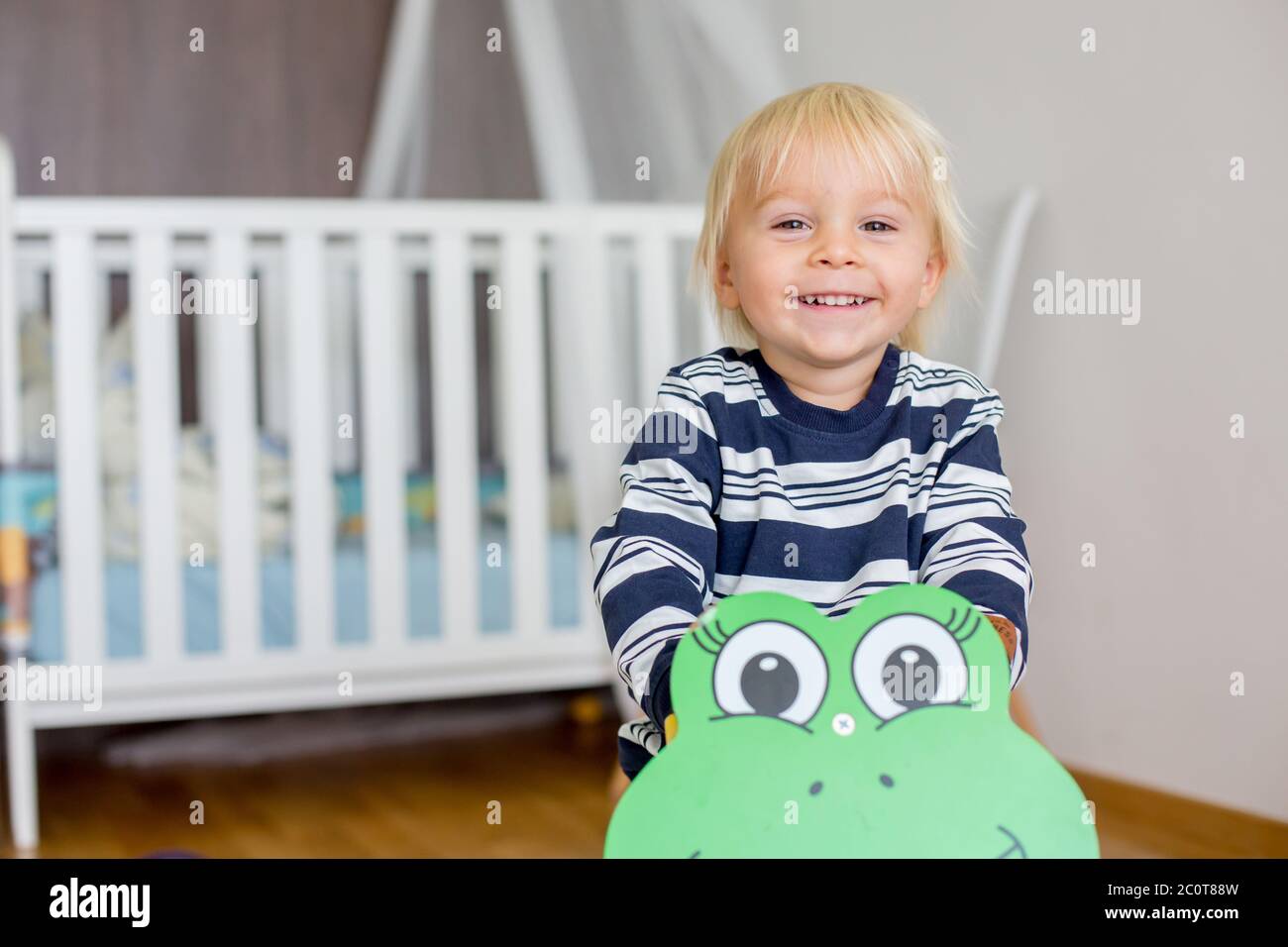Little cute toddler boy, playing with rocking frog swing at home in ...