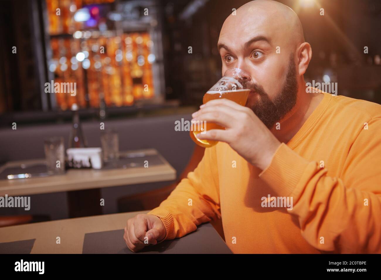 Bald man looking overwhelmed, drinking delicious beer at the pub ...