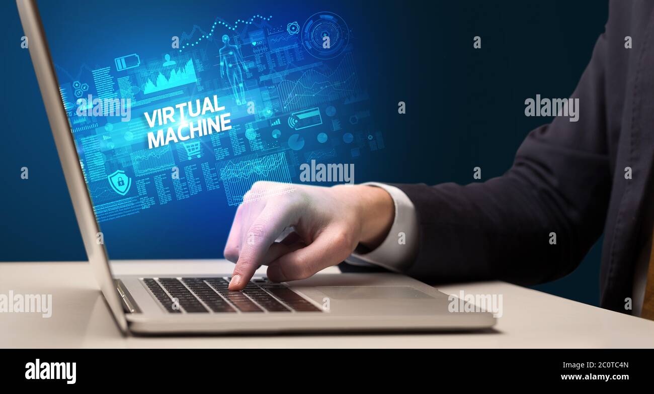Businessman working on laptop with VIRTUAL MACHINE inscription, cyber ...