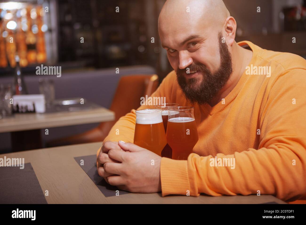 Bearded man smiling devilishly to the camera embracing three beer ...