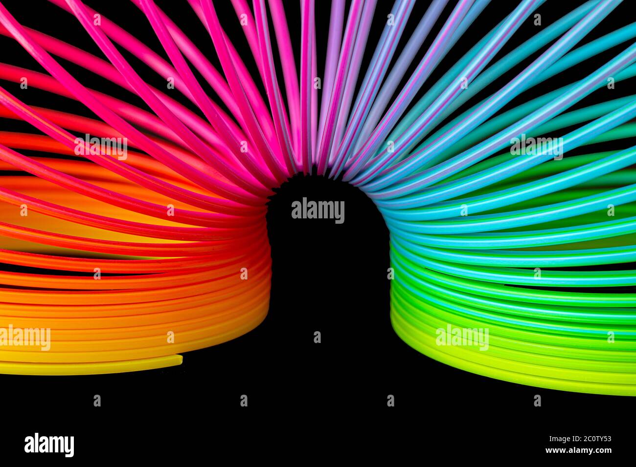 Multicolored plastic slinky closeup isolated against black background ...