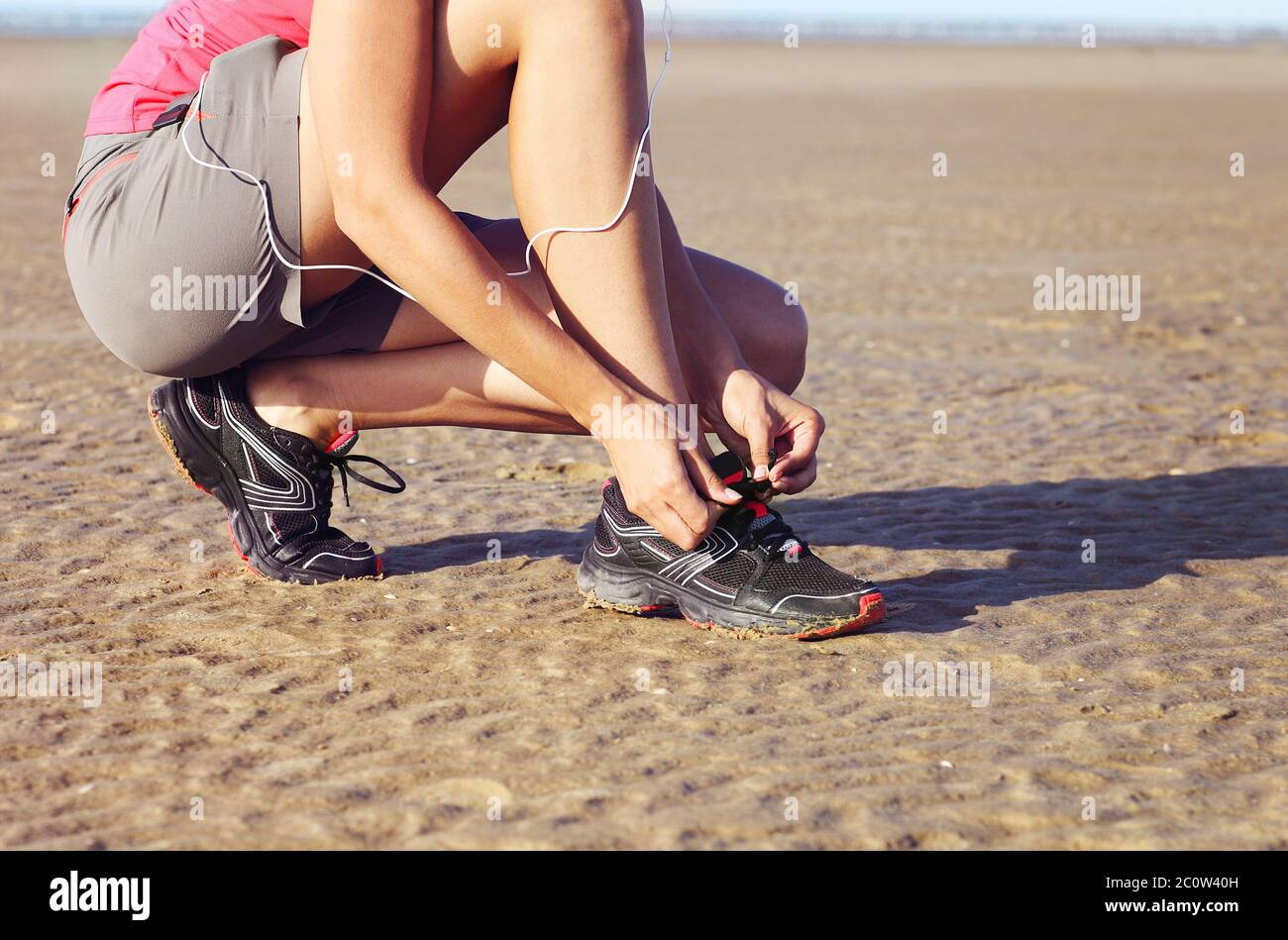 Young woman runner tying shoelaces Stock Photo - Alamy