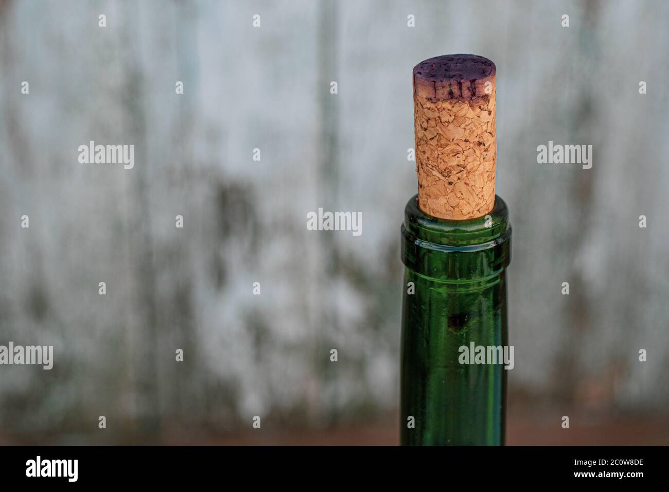 Transparent green glass bottleneck closed with cork stopper wet by dark ...