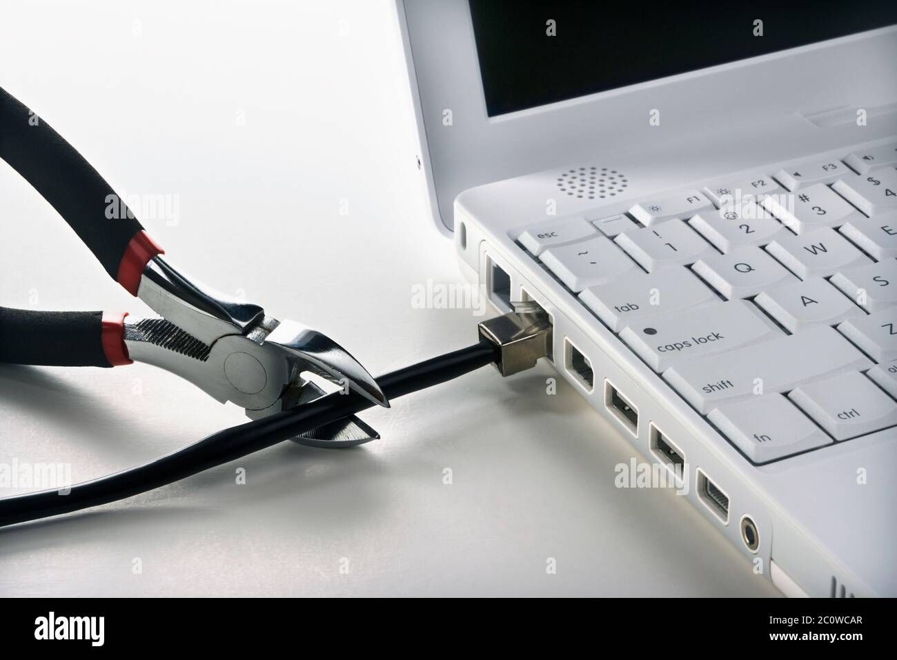 Wire cutters cutting a black Ethernet cable connected to a laptop ...