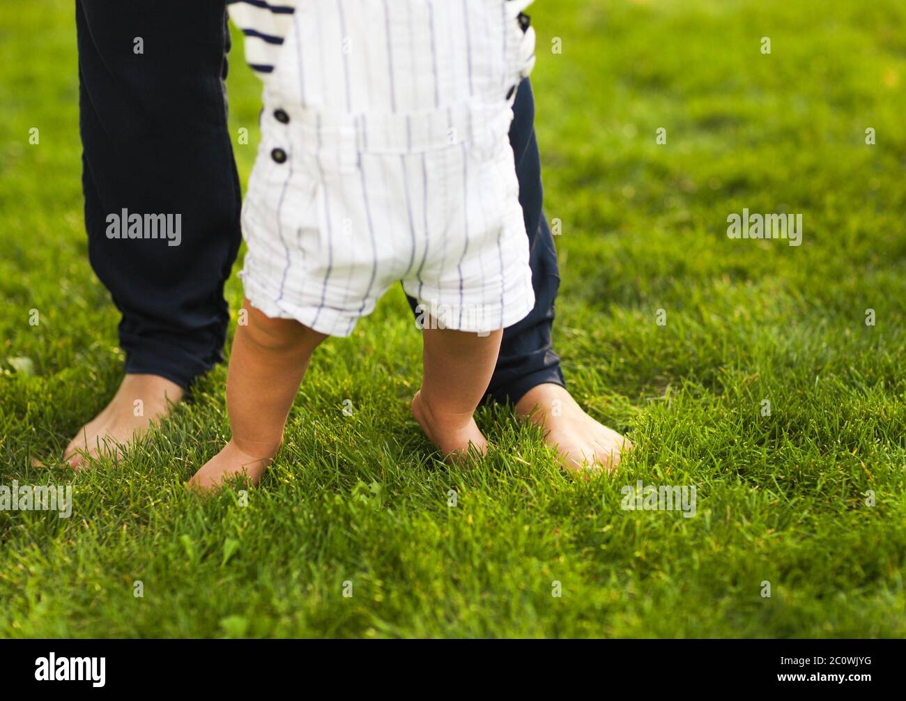 Baby boy taking first steps and mother helping Stock Photo - Alamy