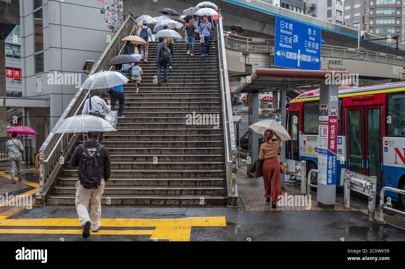 Pedestrian crowd at overpass pedestrian bridge stairs during a rainy ...