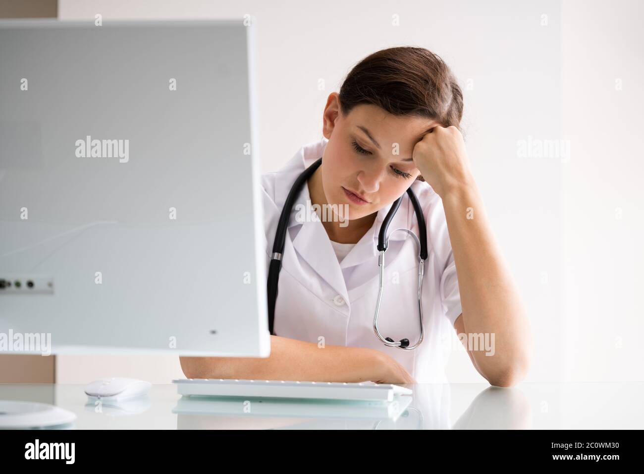 Frustrated Overworked Sad Doctor At Computer In Hospital Stock Photo ...