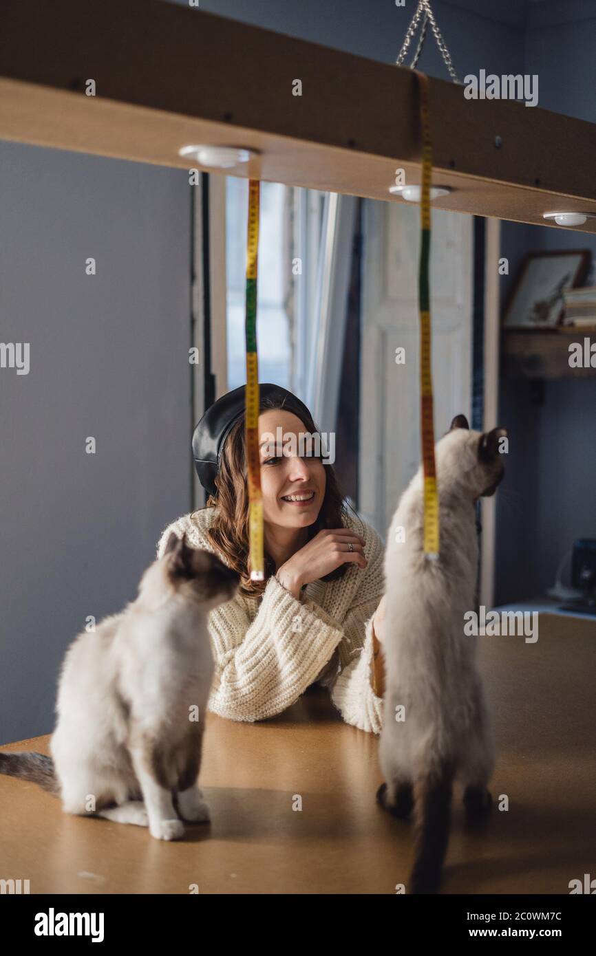 Lovely woman playing with Siamese cats at home. Friendship between ...