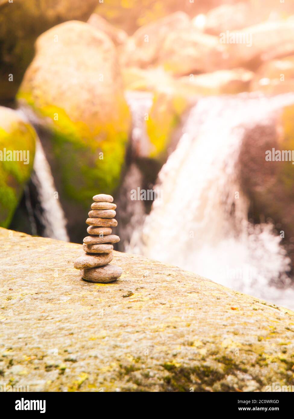 Balancing stone pyramid of pebbles with river waterfall on background ...