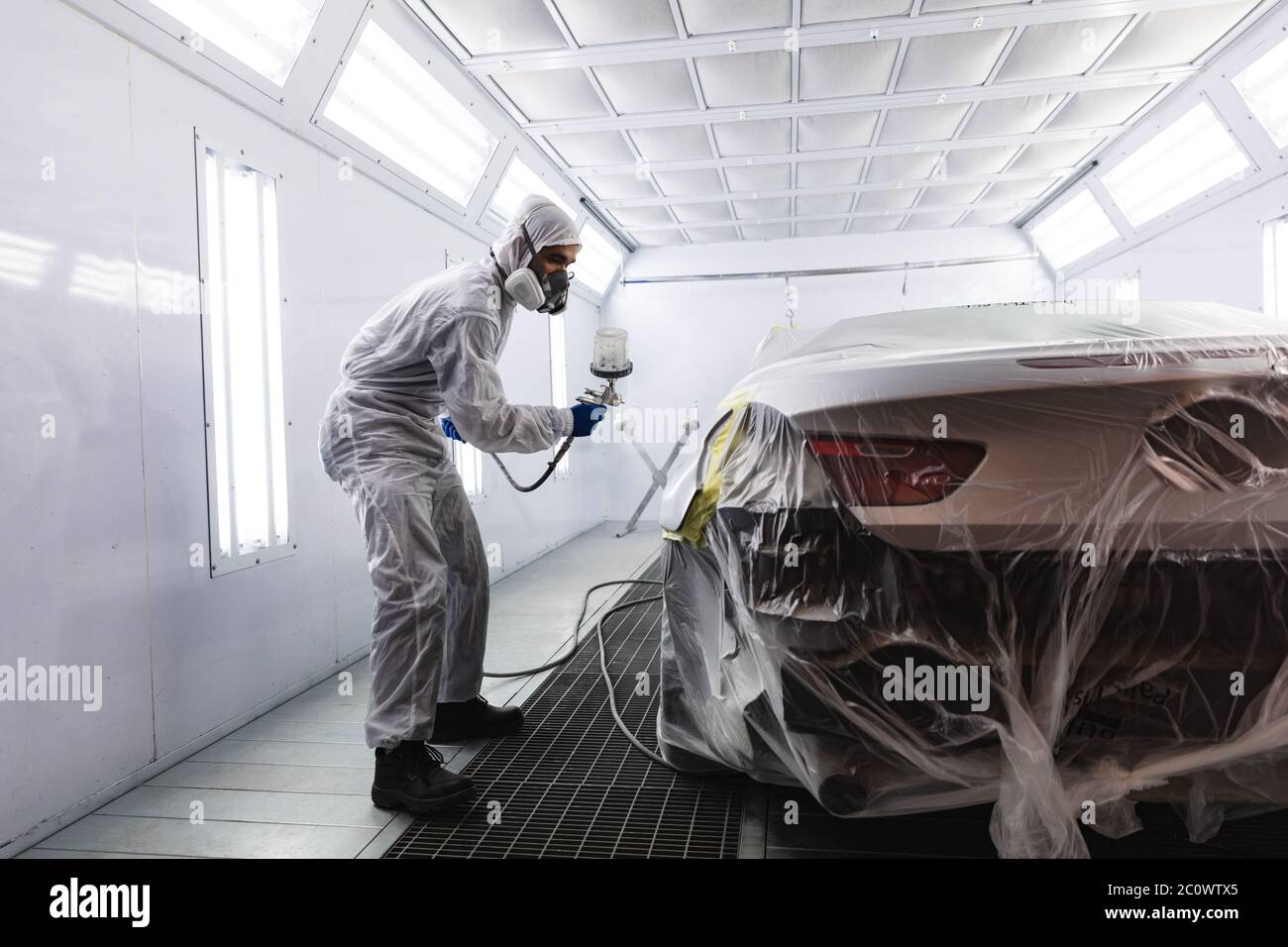 Mixed race car painter painting a car Stock Photo - Alamy
