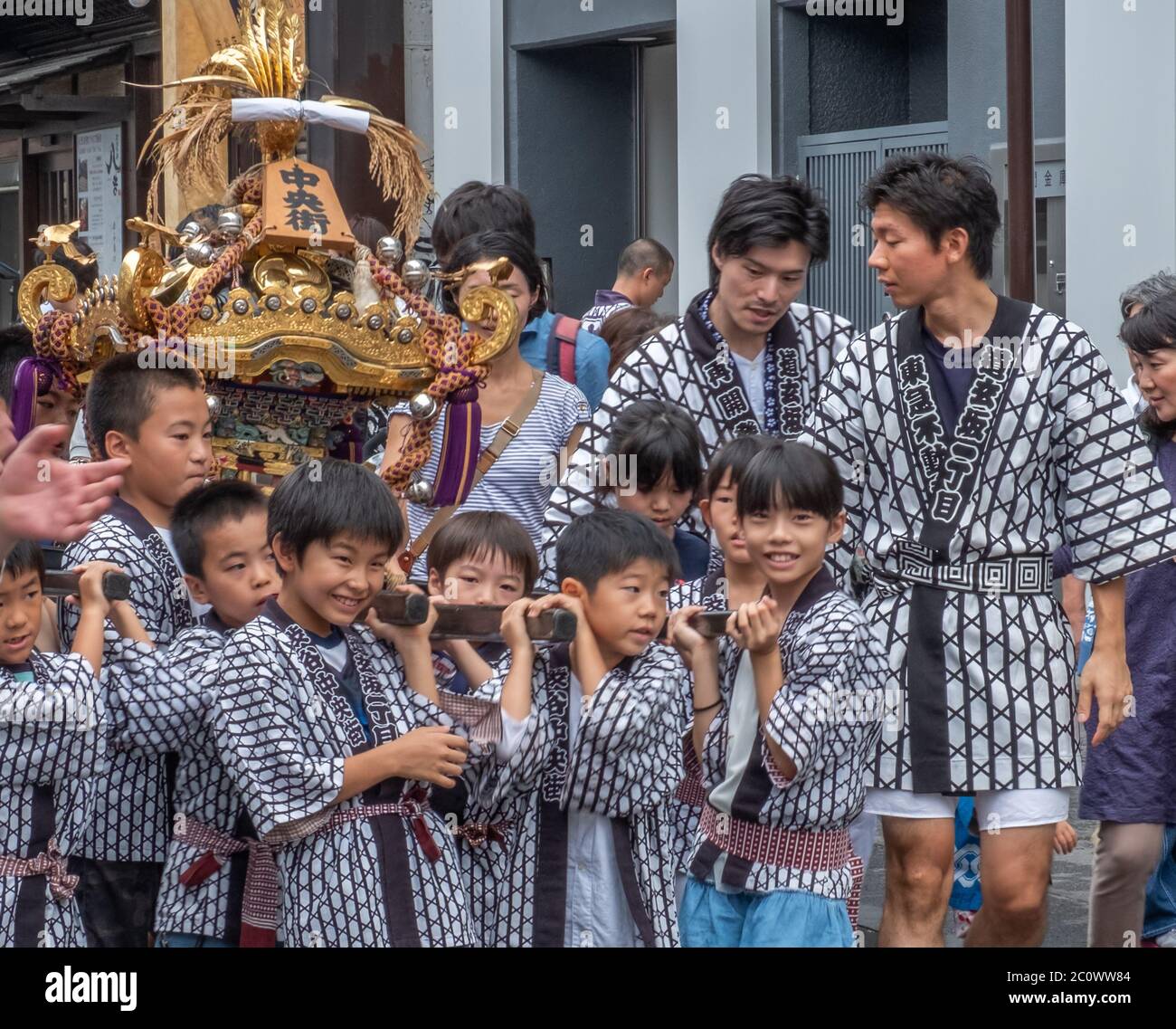 Children carrying a portable shrine or mikoshi in a street procession ...