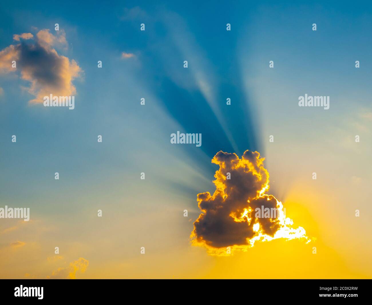 Sun rays from the evening sun behind small cloud Stock Photo - Alamy