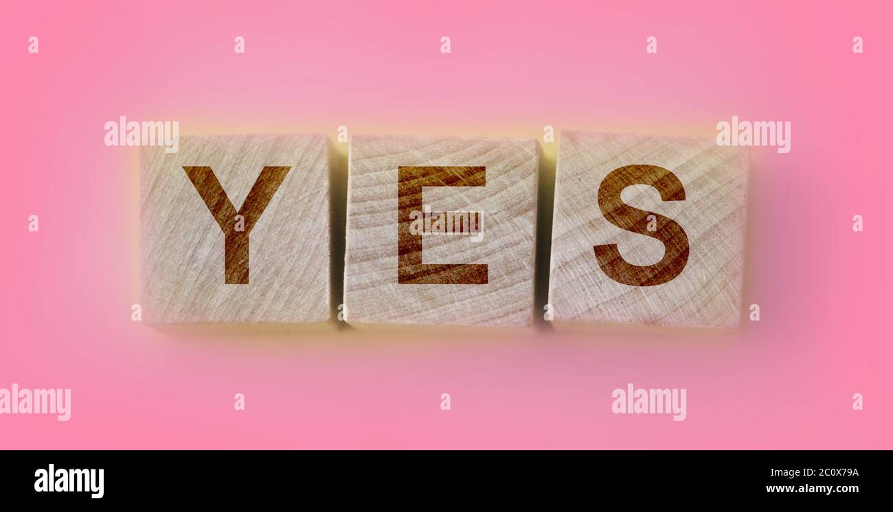 Wooden cubes with word YES on pink table. Positive answer and positive ...