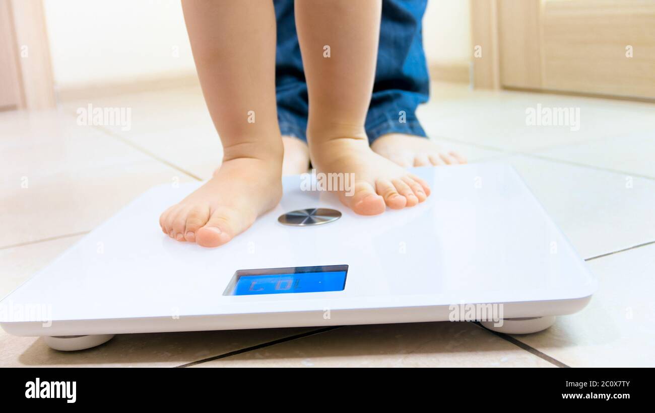 Little child's feet standing on floor digital scales at home Stock ...
