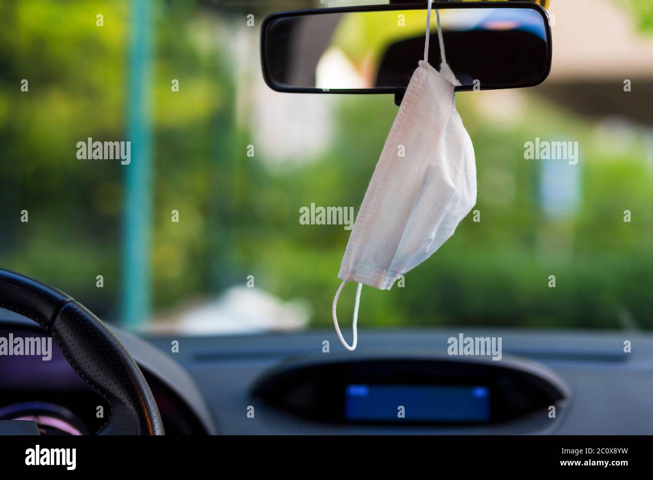Face mask hung in car's rear-view mirror Stock Photo - Alamy