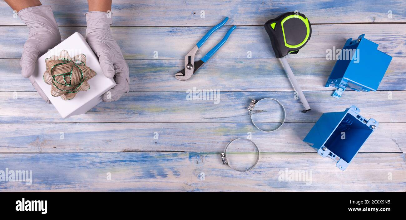 Composition with hardware tools. Hands holding gift box with rubber ...