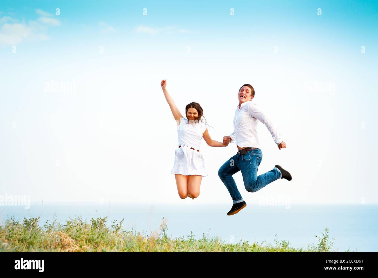Young happy couple jumping on the beach Stock Photo - Alamy
