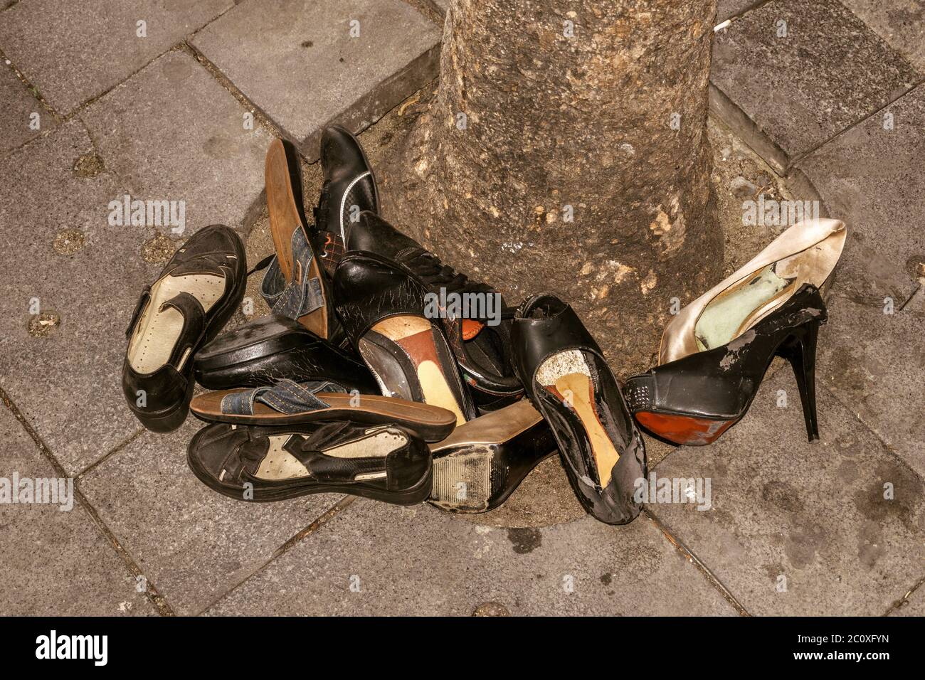 old shoes thrown at the bottom of a tree on the street, closeup. night ...