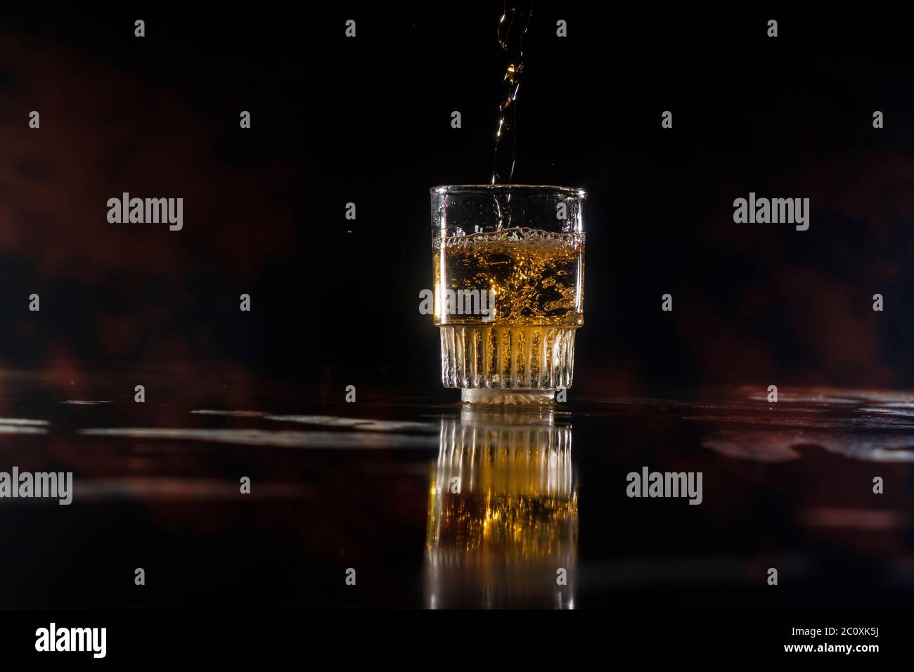 A liqueur falling down into a cup with some red smoke at night Stock ...