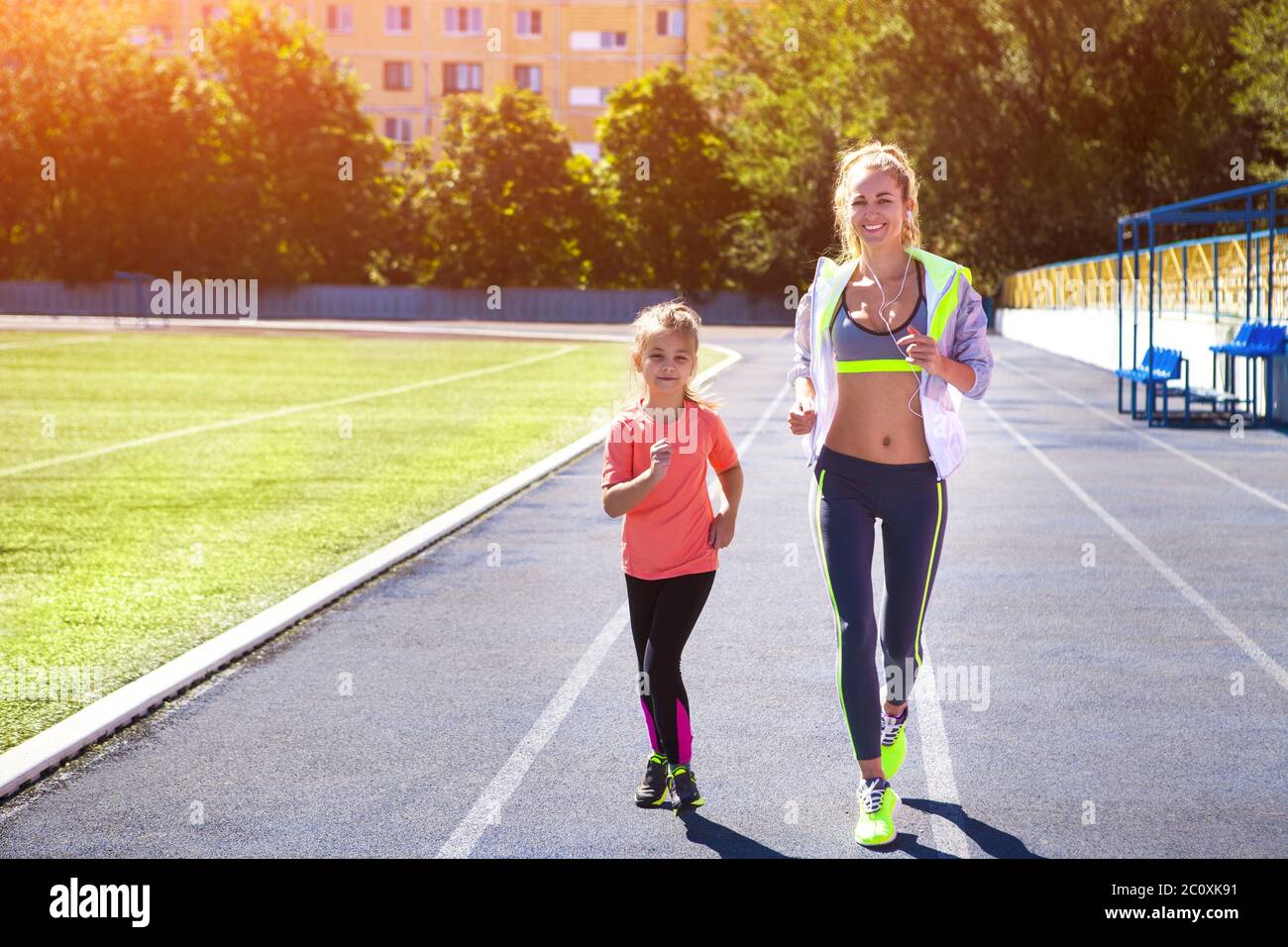 Mother and little daughter are doing exercise in the stadium Stock ...