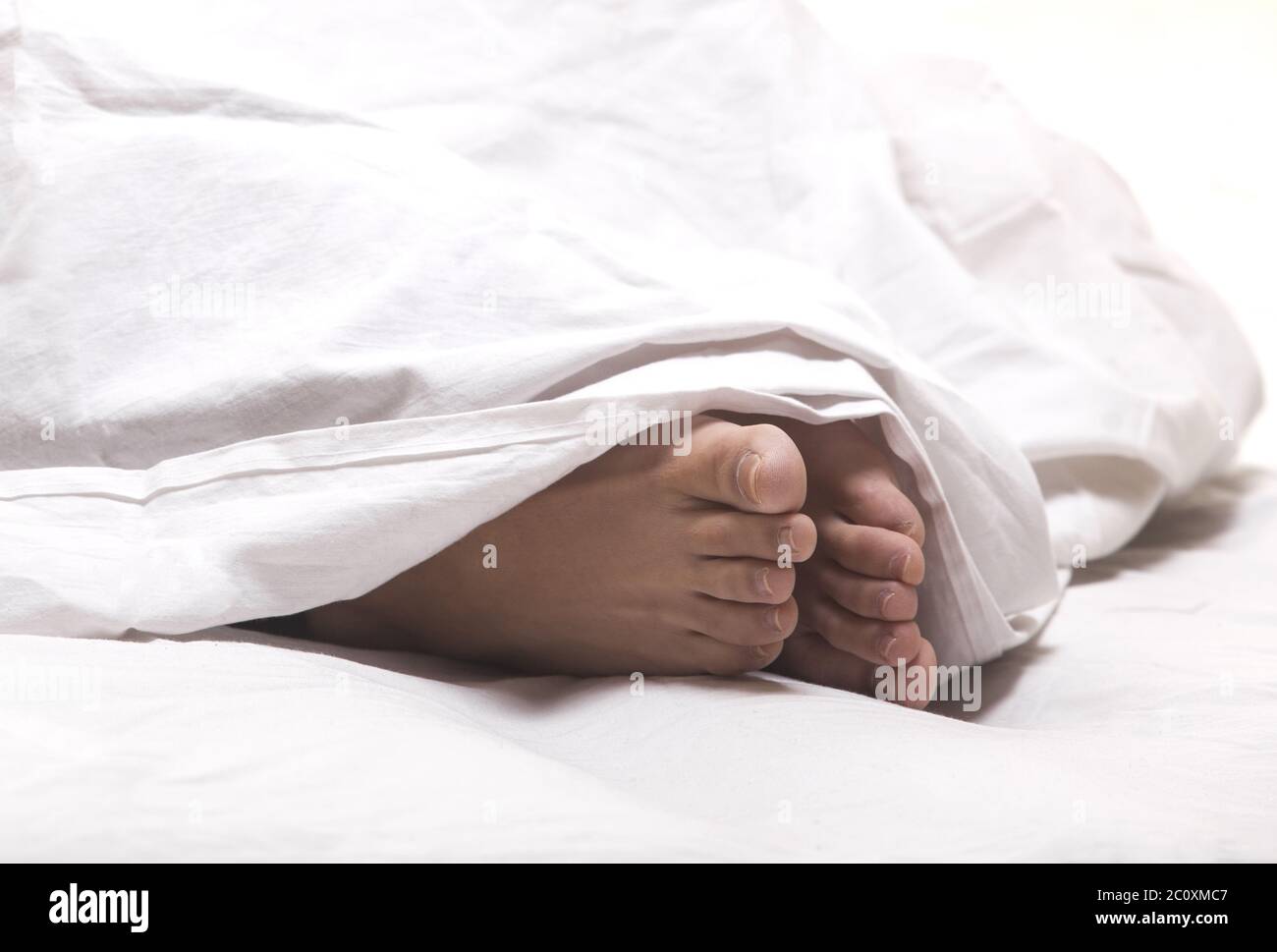 Feet on white sheets Stock Photo - Alamy