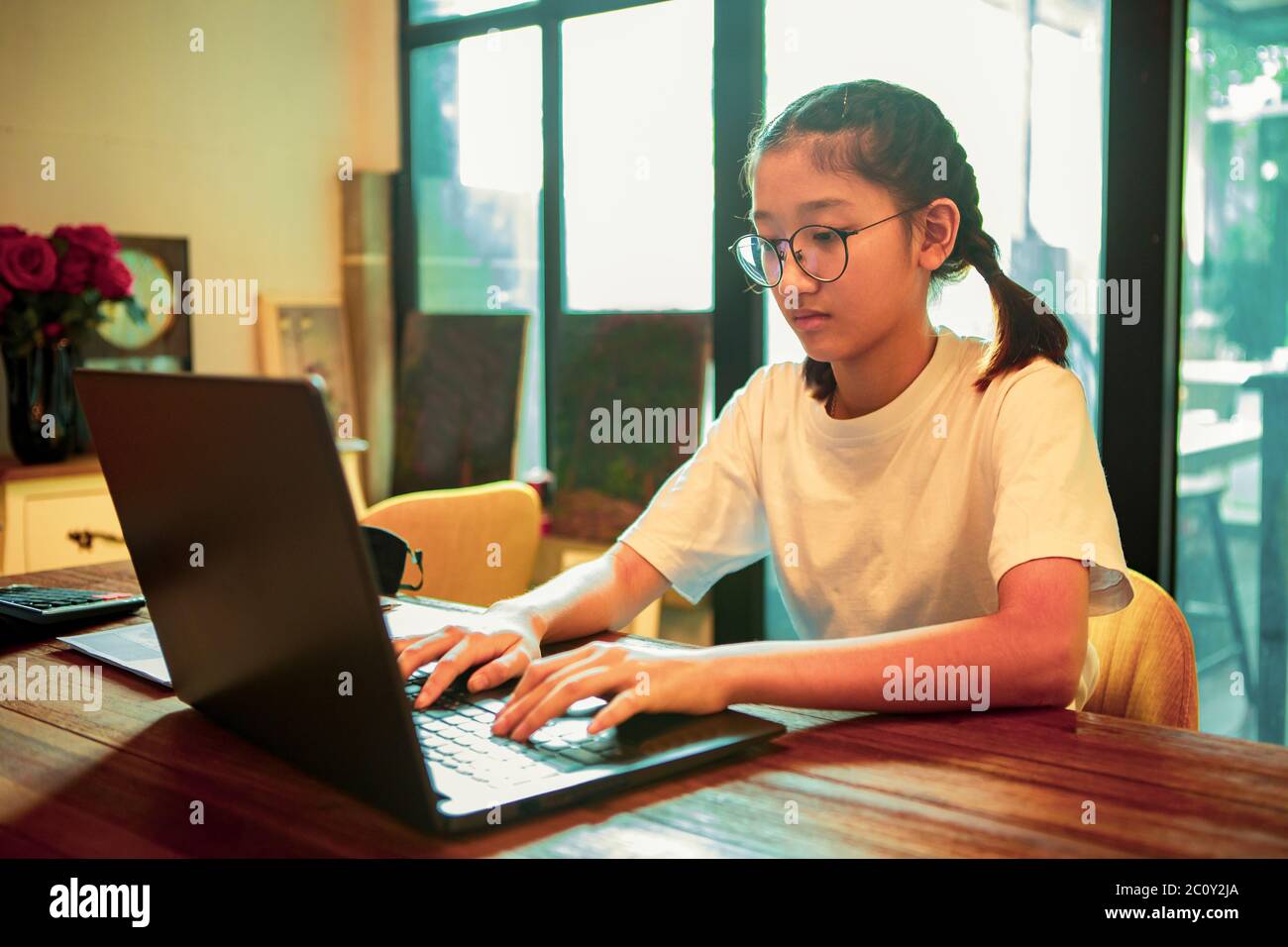asian teenager sitting in homing living room and typing on computer ...